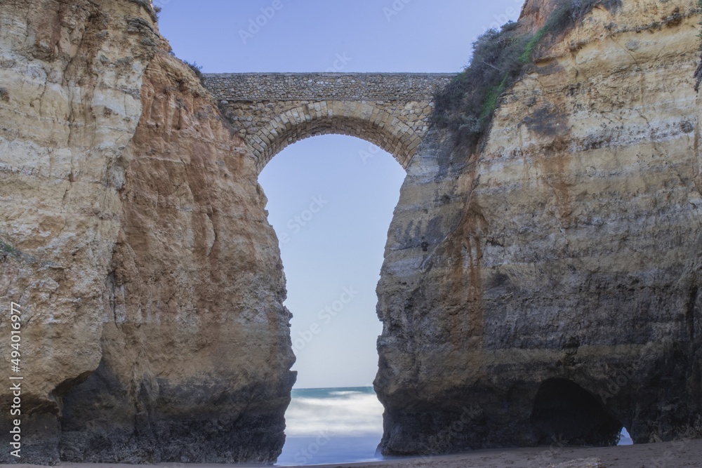 Old stone masonry Roman bridge in Praia dos Estudantes beach in Lagos ...