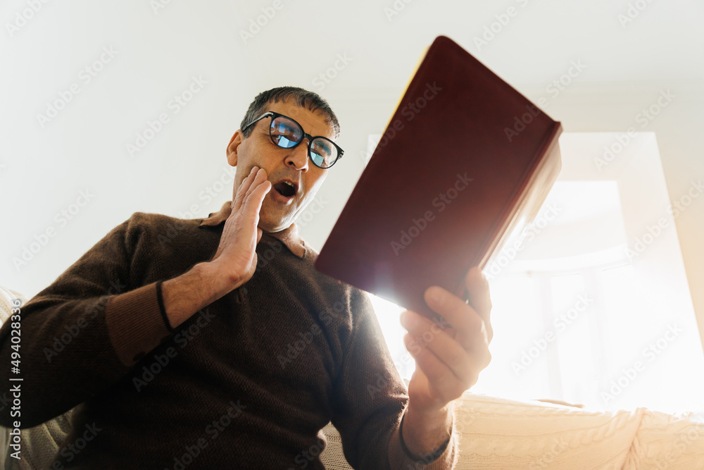 Foto de old indian man reading a book at home wearing glasses scared in ...
