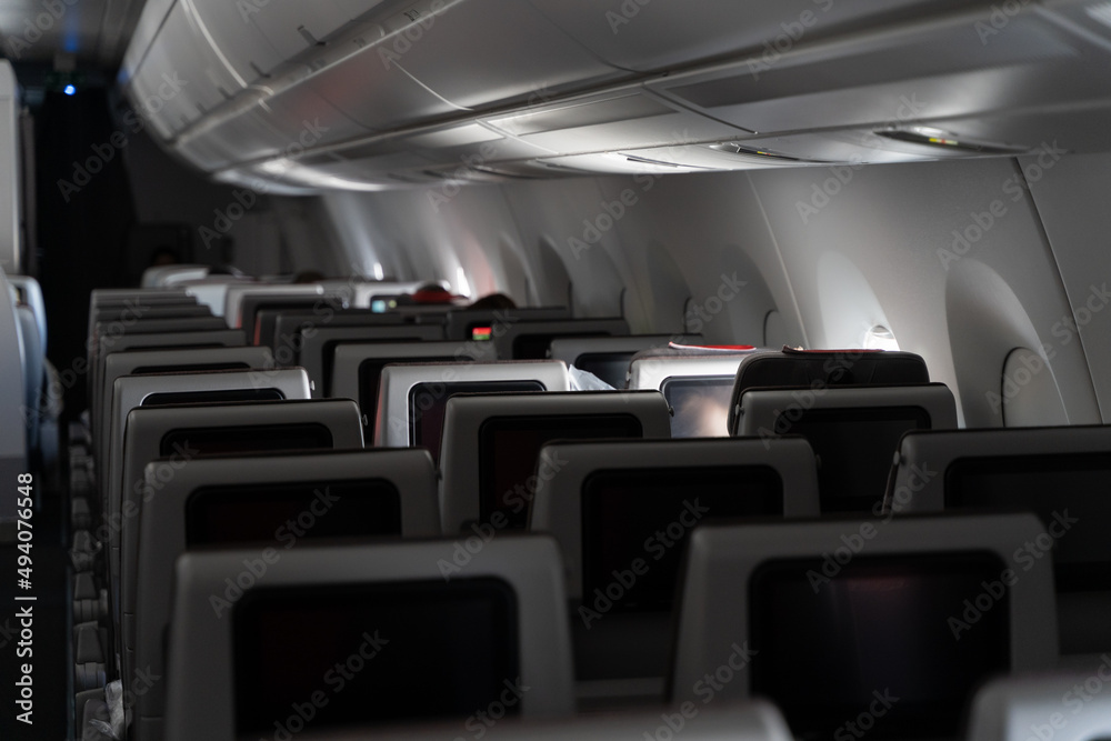 Airplane interior with rows of three seats by window and over head ...