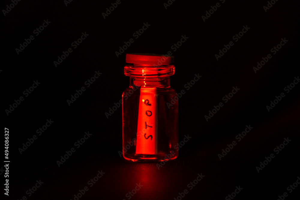 Paper roll with stop word in glass bottle isolated on black backdrop ...