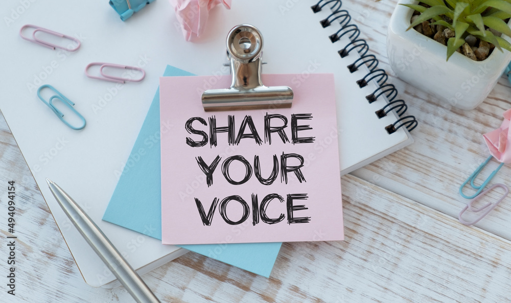 note with the message of share your voice, with desk background Stock ...