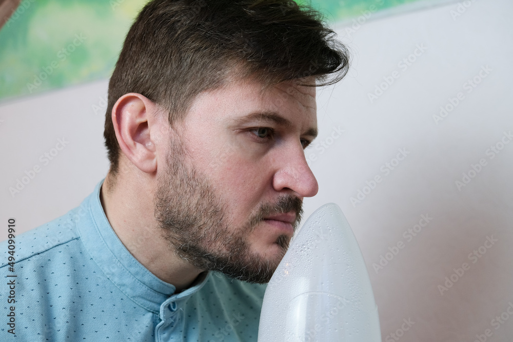 An adult man breathes steam, treats the airways with a nebulizer at ...