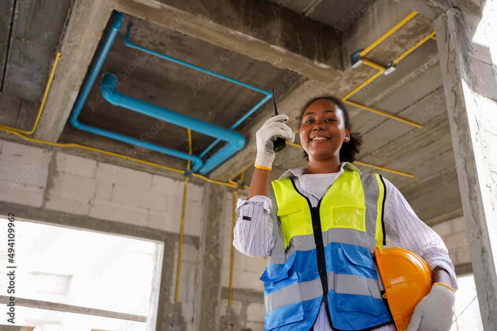 A black female engineer working at a construction site, she wears a ...