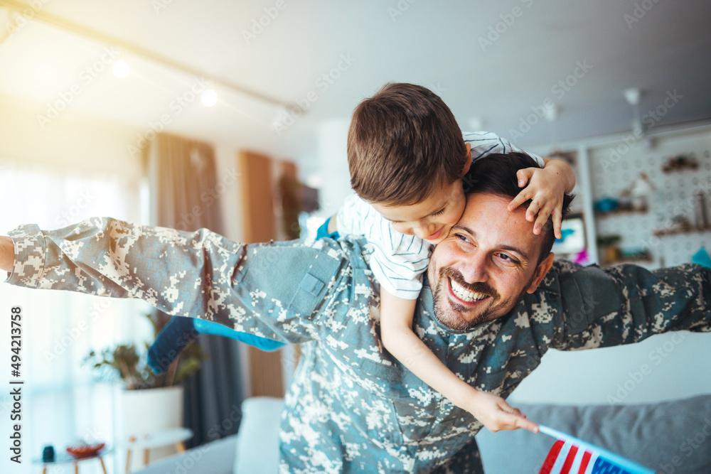 Soldier and his little son hugging at home. Smiling soldier reunited ...