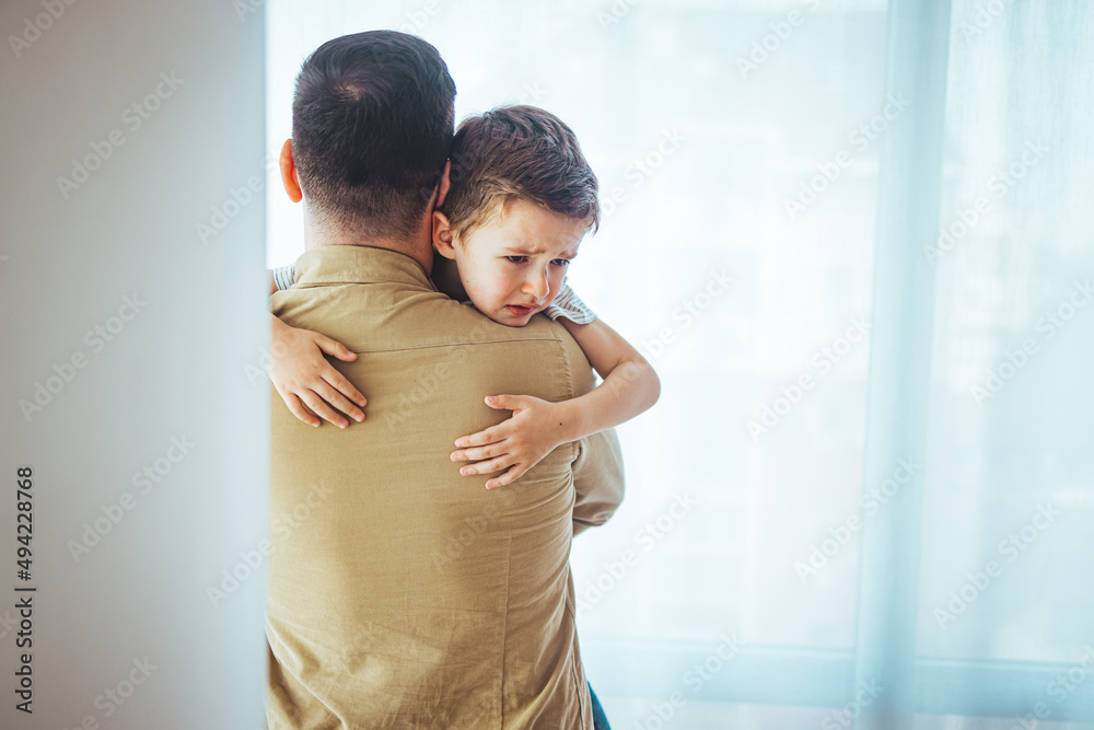 Closeup Sad young blond boy crying on father hands indoor. Man holds ...