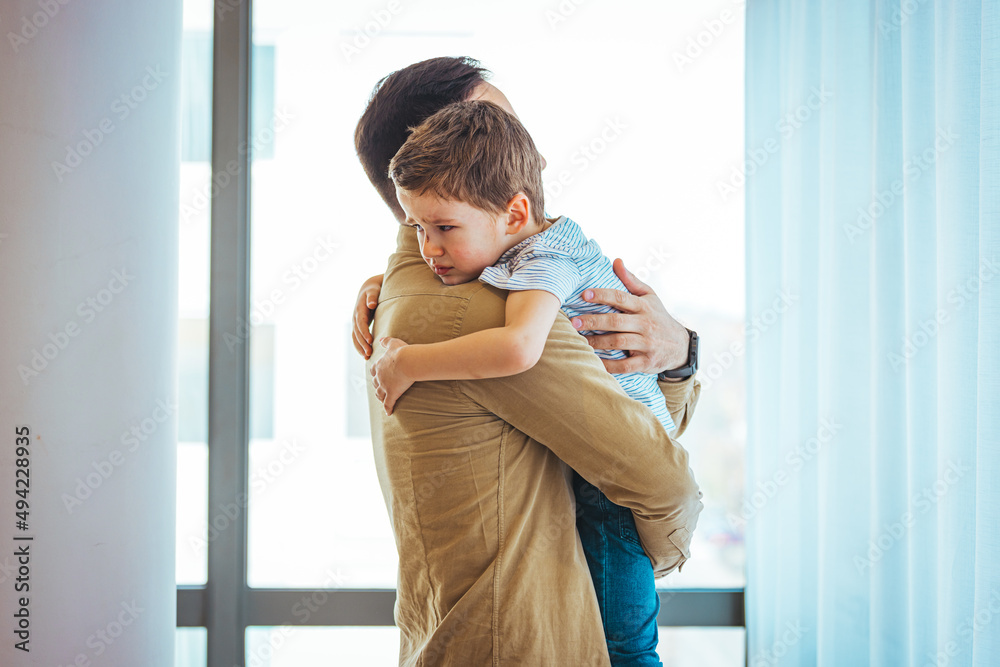 Closeup Sad young blond boy crying on father hands indoor. Man holds ...