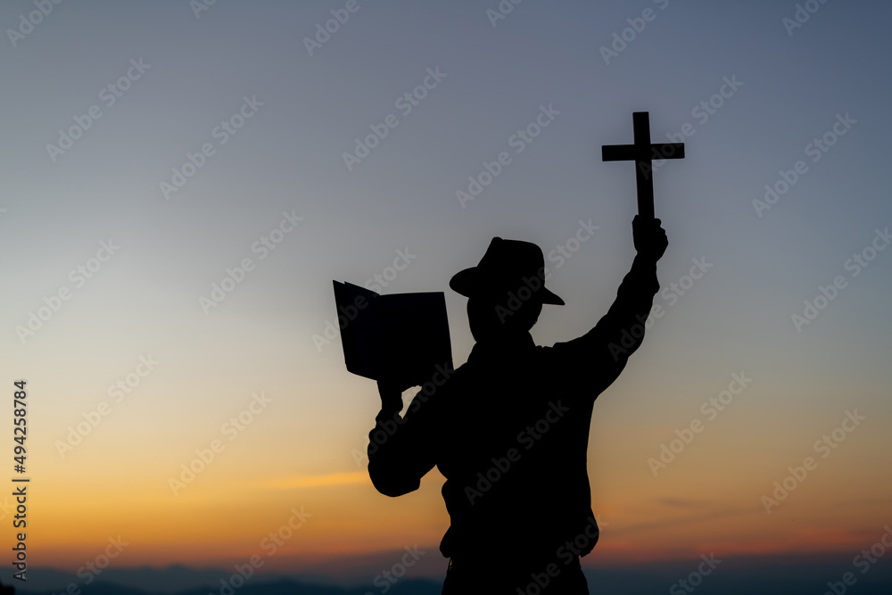 Silhouette of a young Christian man who is praying on the holy cell in ...