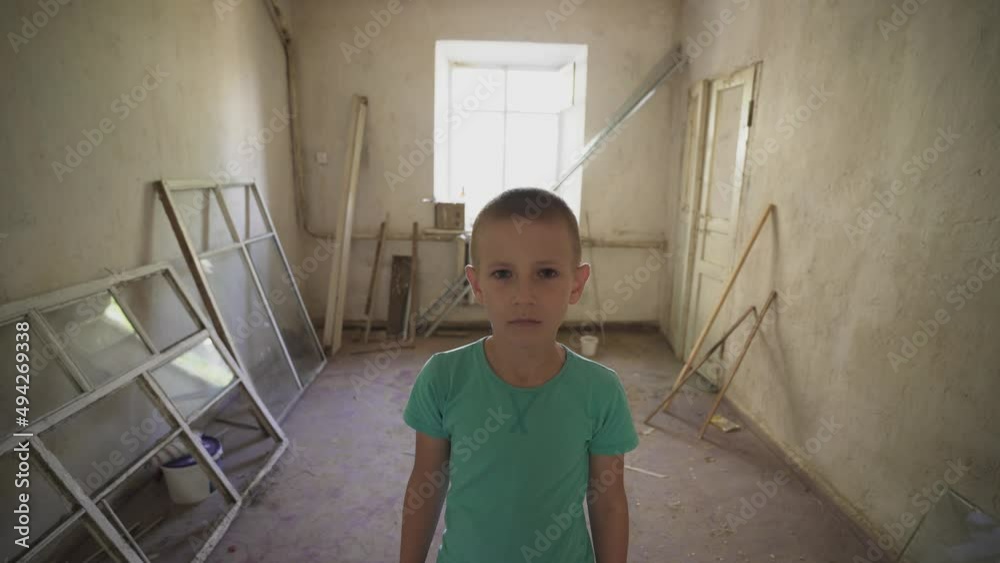 portrait Ukrainian boy in a destroyed house. a homeless child in dirty ...