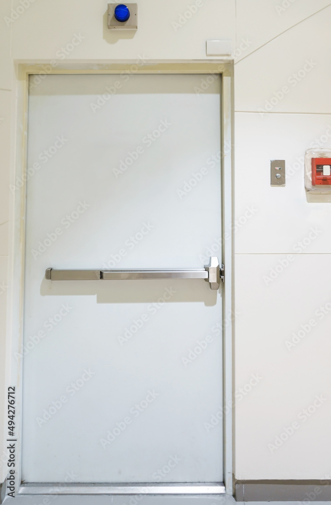 Building emergency exit with exit sign on door and fire extinguisher on ...