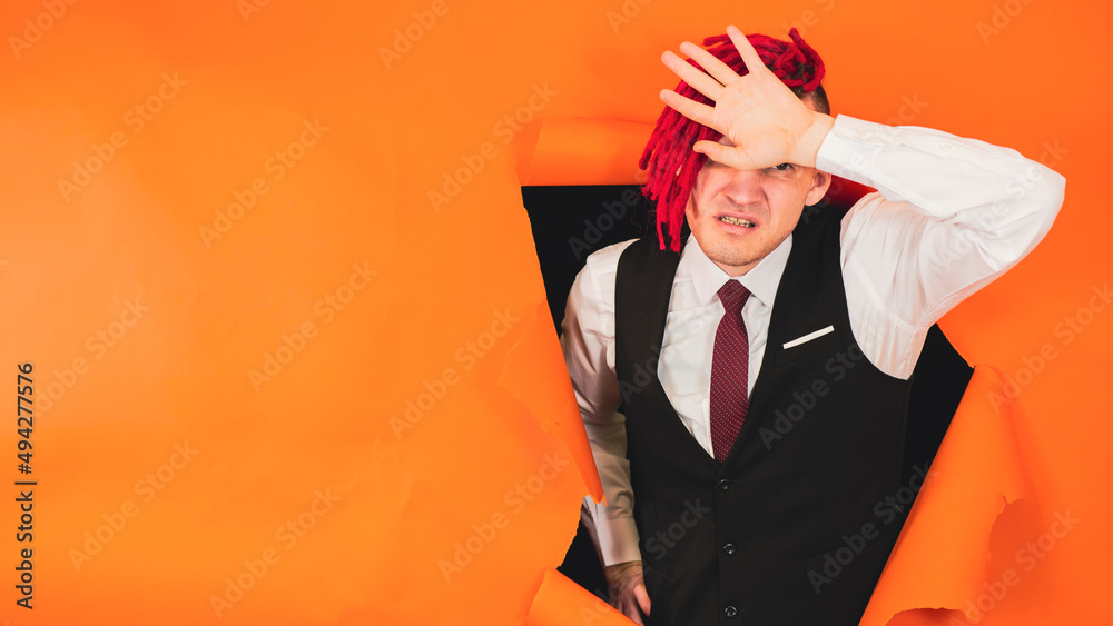 Young upset man posing in hole of orange background. Perplexed male ...