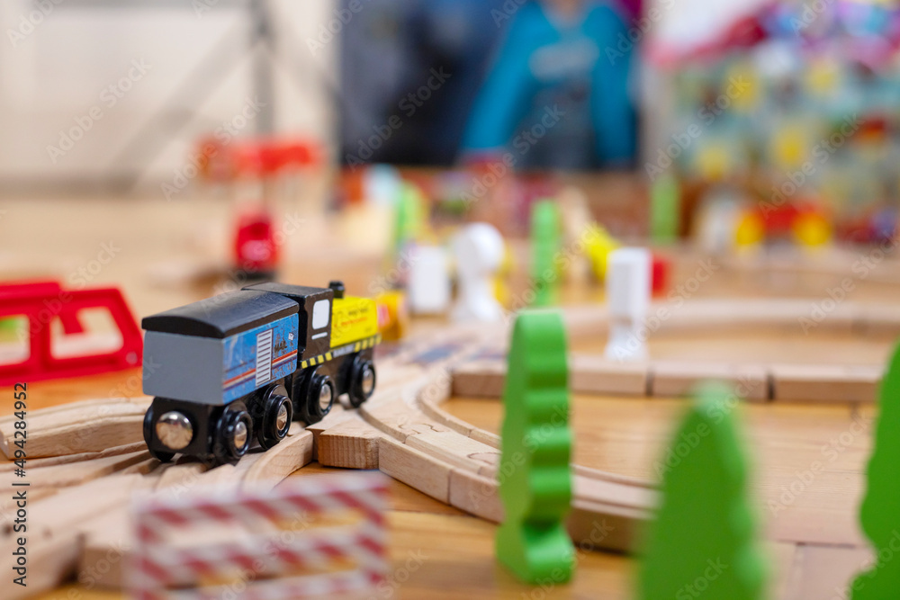 Wooden toy train on railroad with brick town on floor. Toys for kids ...