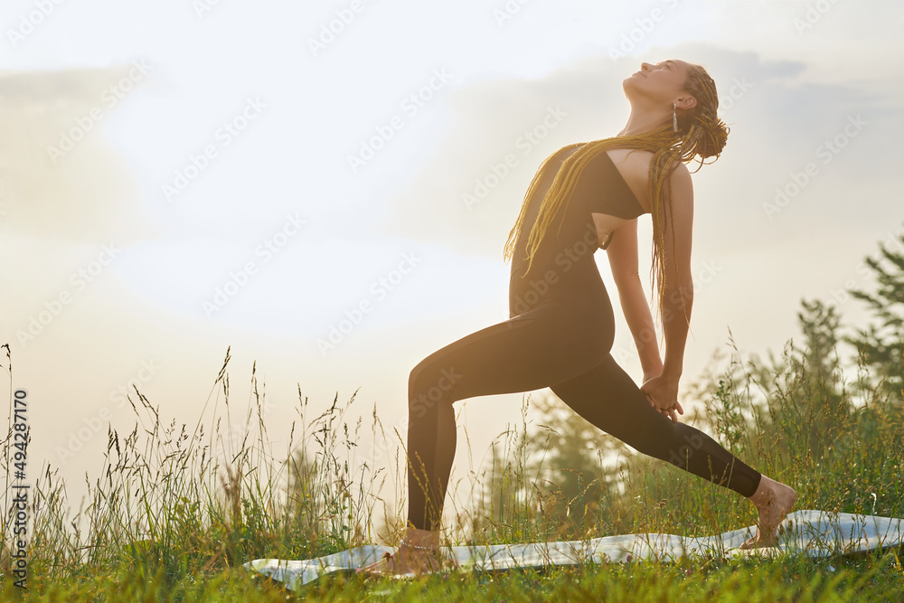 Side view of sporty woman practicing yoga. Young female stepping with ...