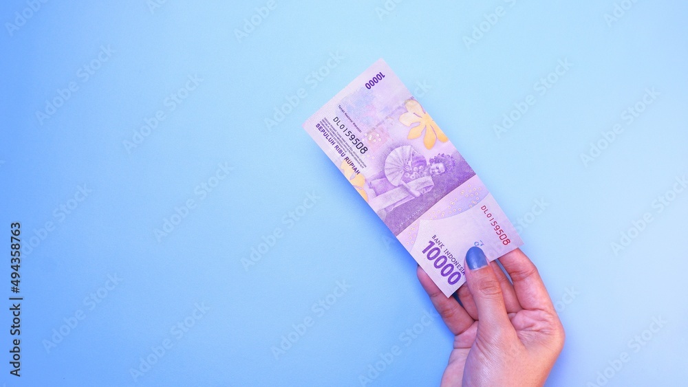 Indonesian Rupiah the official currency of Indonesia. woman's hand is ...