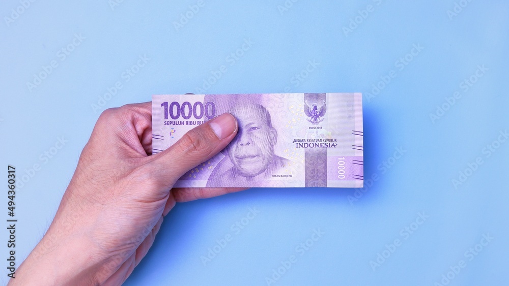 Indonesian Rupiah the official currency of Indonesia. Man's hand is ...