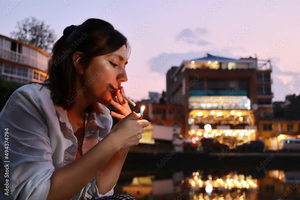 woman lighting a cigarette with night city view Stock Photo | Adobe Stock
