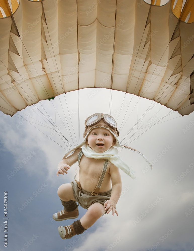 Child pilot. A kid in the form of a pilot flies on a parachute against ...