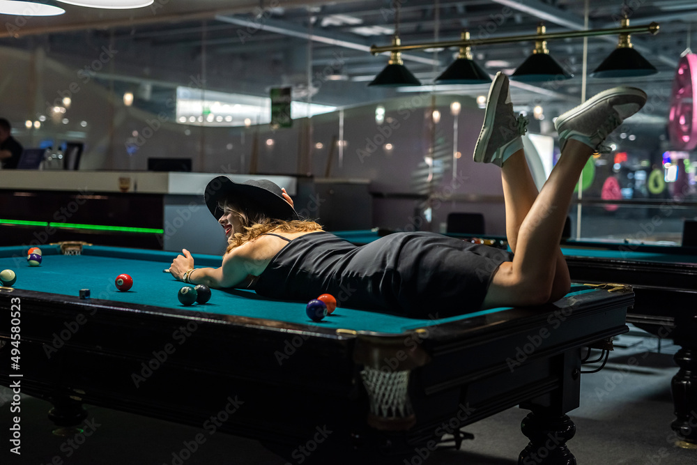 Sexy female pool player wear black dress lying on billiard table Stock ...
