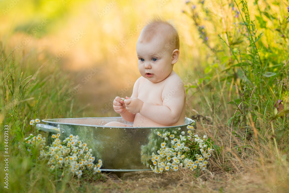 cute baby is bathing in an iron basin in the garden. outdoor water ...