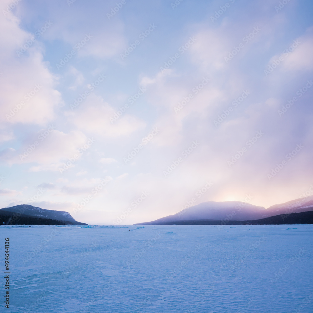 Ice pressure ridge on a frozen lake shore. Mountain peaks in the ...