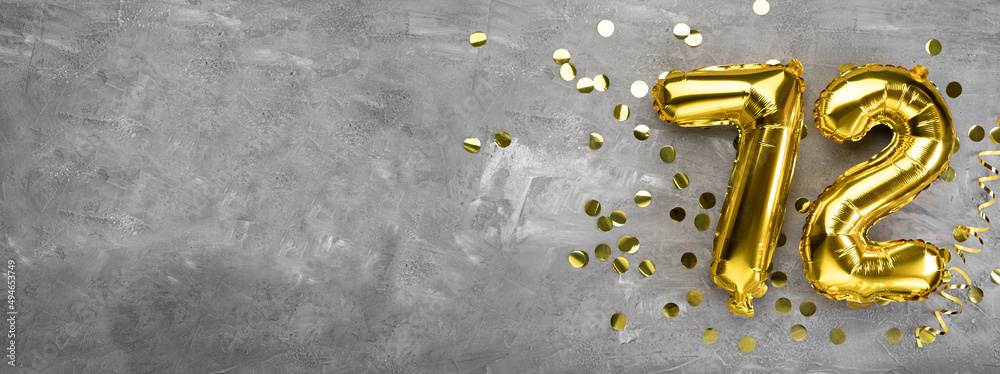 Yellow foil balloon number, number seventy two on a concrete background ...