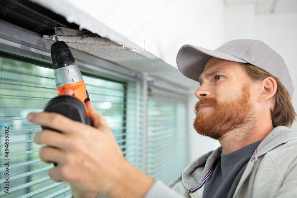 man installing roller shutter on window Stock Photo | Adobe Stock
