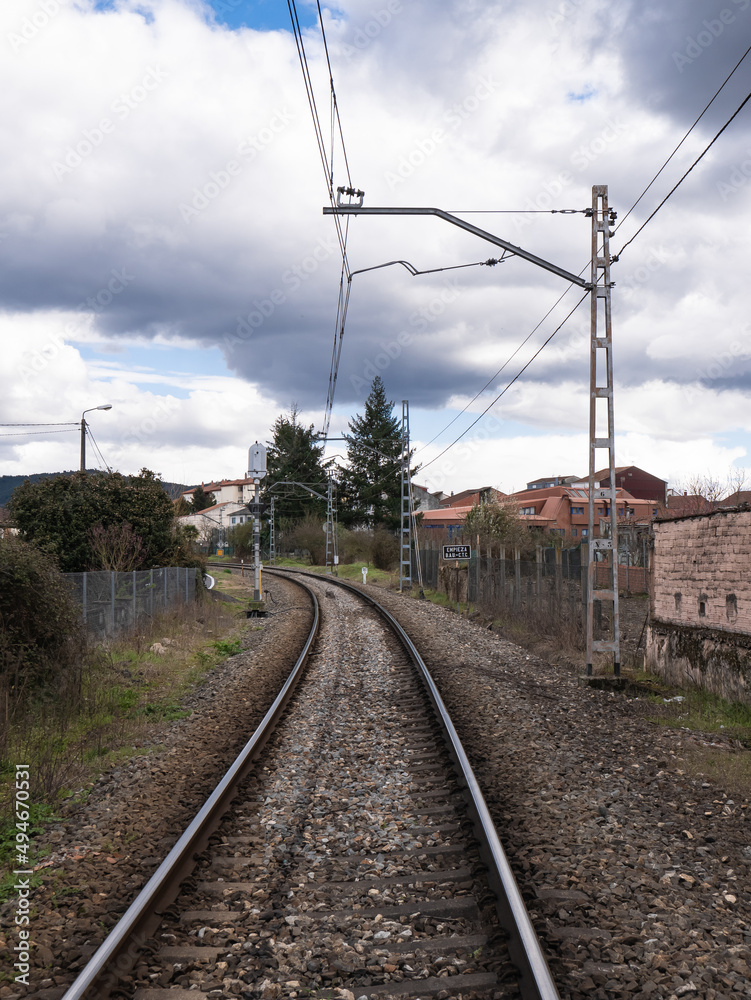 Fotka „Train track on a curved path under the catenary wires and a sign ...
