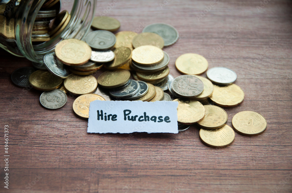 Hire purchase text on torn paper with jar, coins, and wooden table ...