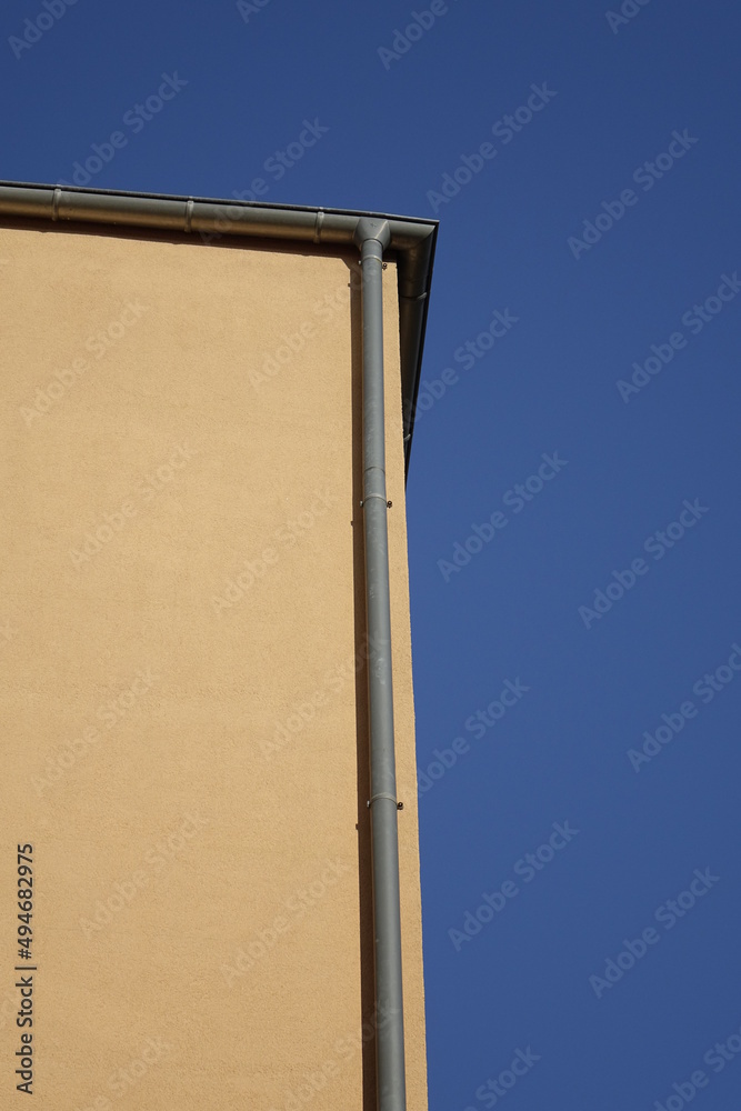 Upper right corner of yellow house wall with rain gutter, clear blue ...