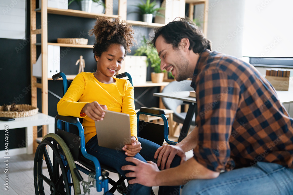 Child with disability in wheelchair at home having fun with father ...