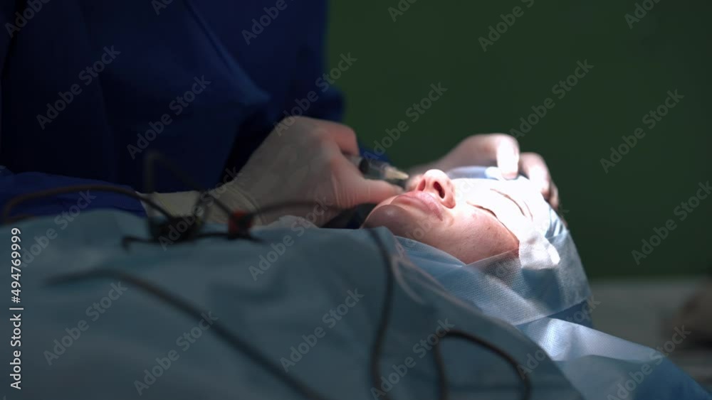 Young woman lying on surgery bed with surgeon hands injecting ...