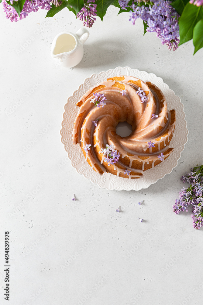 Classic Vanilla Bundt Cake with Sugar Glaze and lilac flowers on white ...