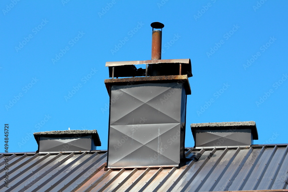 Elongated narrow concrete chimney covered with dark grey metal sheet ...