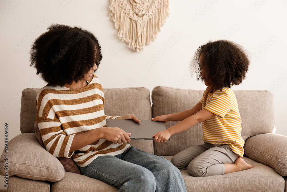 Two black girls of different age fighting for laptop. Younger and older ...
