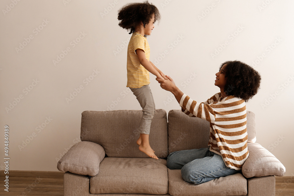 Younger and older sister spending time together at home. Two black ...
