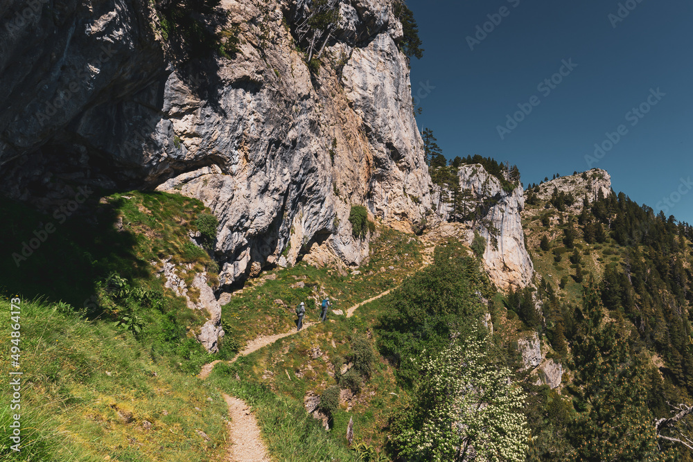 Two mountaineers hiking on a diagonal path under a stone wall. Stock ...