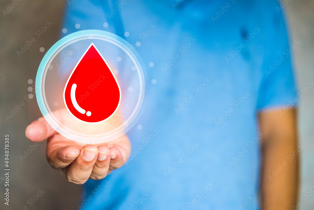Human hand with blood drop symbol on the screen. World blood donor day ...