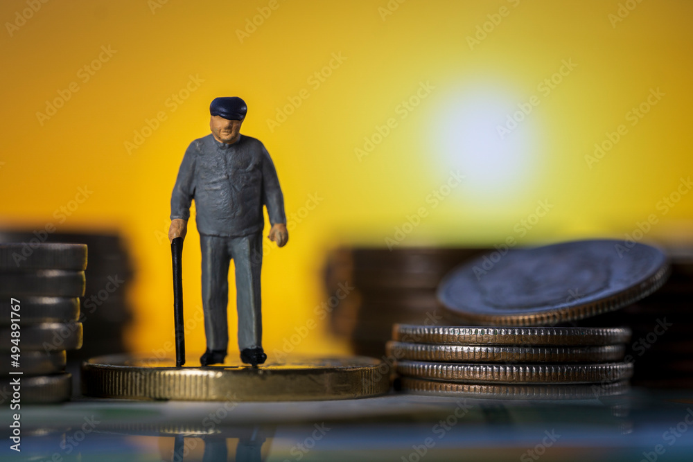 Miniature people old man walking with a cane between coin stacks sunset ...