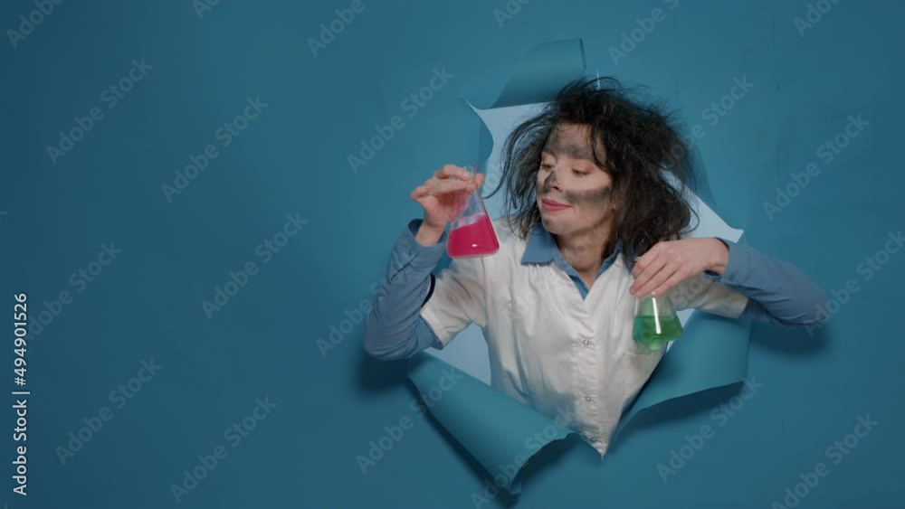 Foolish crazy chemist doing silly grimace and holding beakers after insane chemical explosion ...