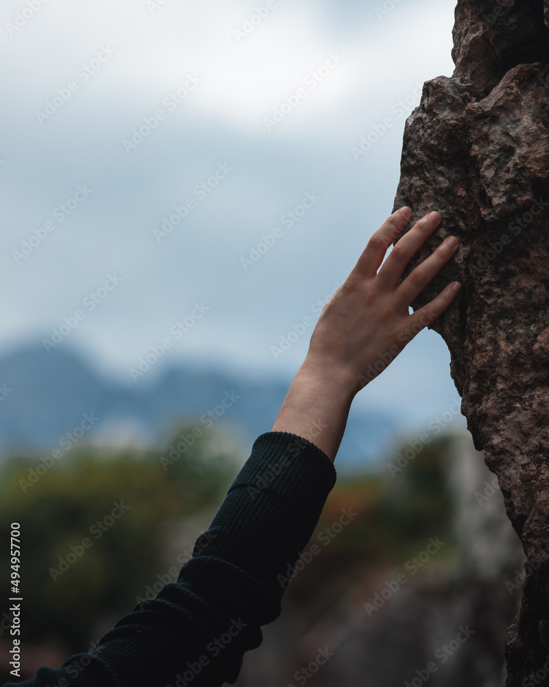 Vertical of a hand touching a piece of rock on a blurry background of ...