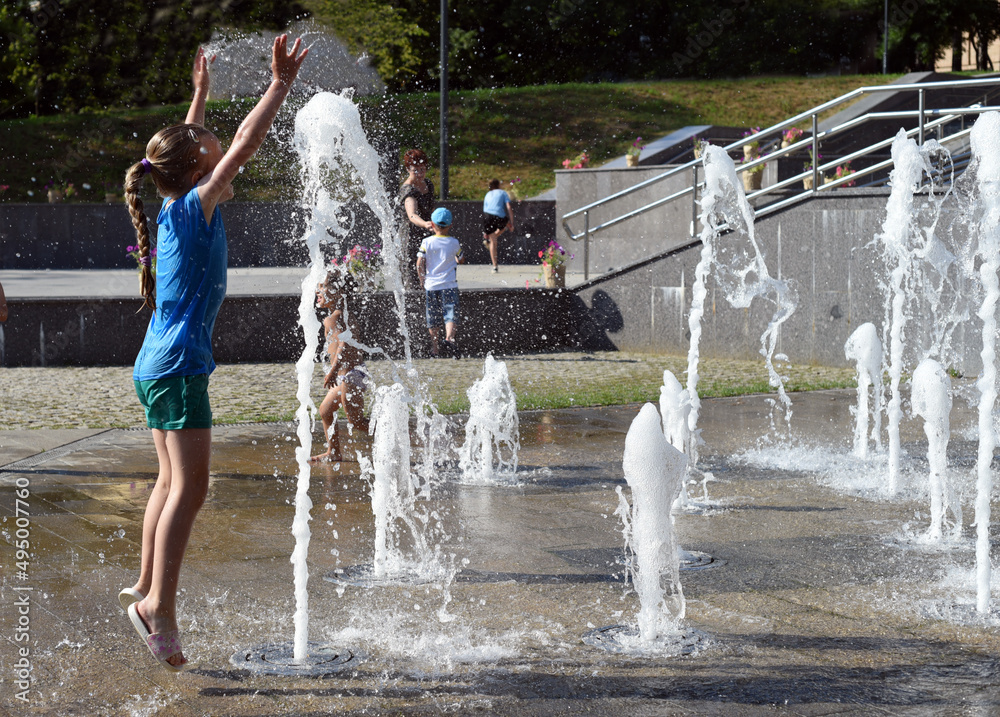 A girl in wet clothes jumped up, stretching her arms up, catching the ...
