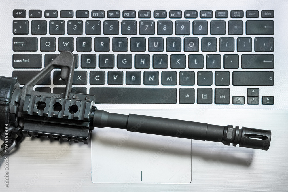 Cyber Warfare. Machine gun on keyboard computer. Fake news. Hybrid war ...
