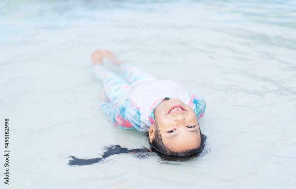 Asian child happy smile or kid girl wearing swimsuit and lying down ...