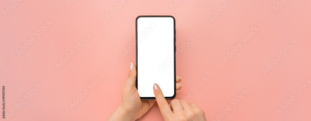 Hand holding cellphone device and touching screen on pink background ...