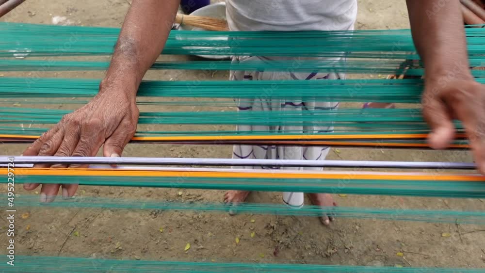 A craftsman's fingers are untying the starch-spray wet thread of lungi ...