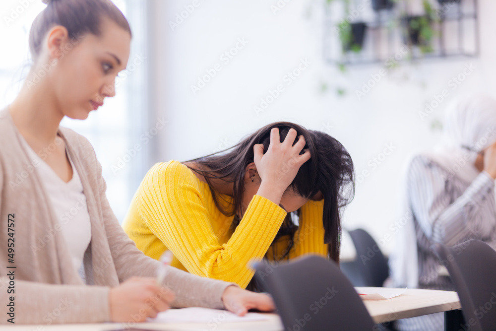 Students taking a test in a classroom. Smart young girl disappointed ...