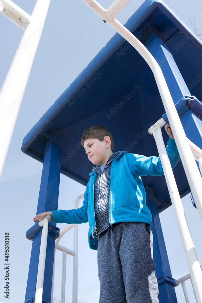Young boy with Autism playing on a playground; boy is wearing blue ...