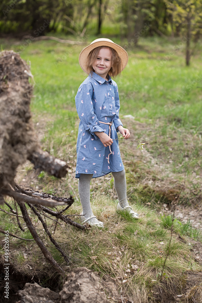 Cute small caucasian girl standing next to a fallen tree with upturned ...