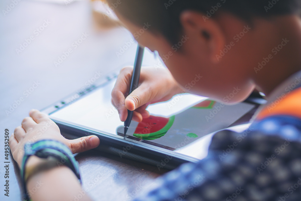 Boy with digital pencil drawing and painting on a tablet at home to ...