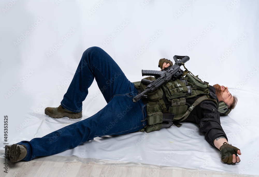 an airsoft player in full gear lies with his arms and legs spread out ...