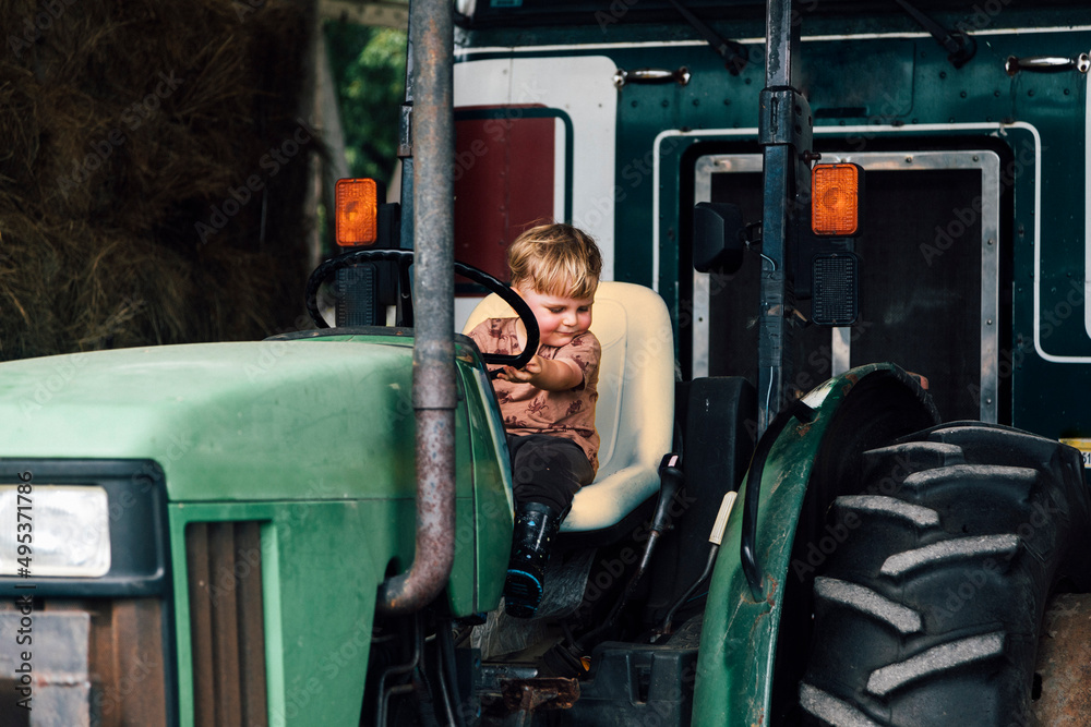 Happy boy sitting on tractor in farm Stock Photo | Adobe Stock